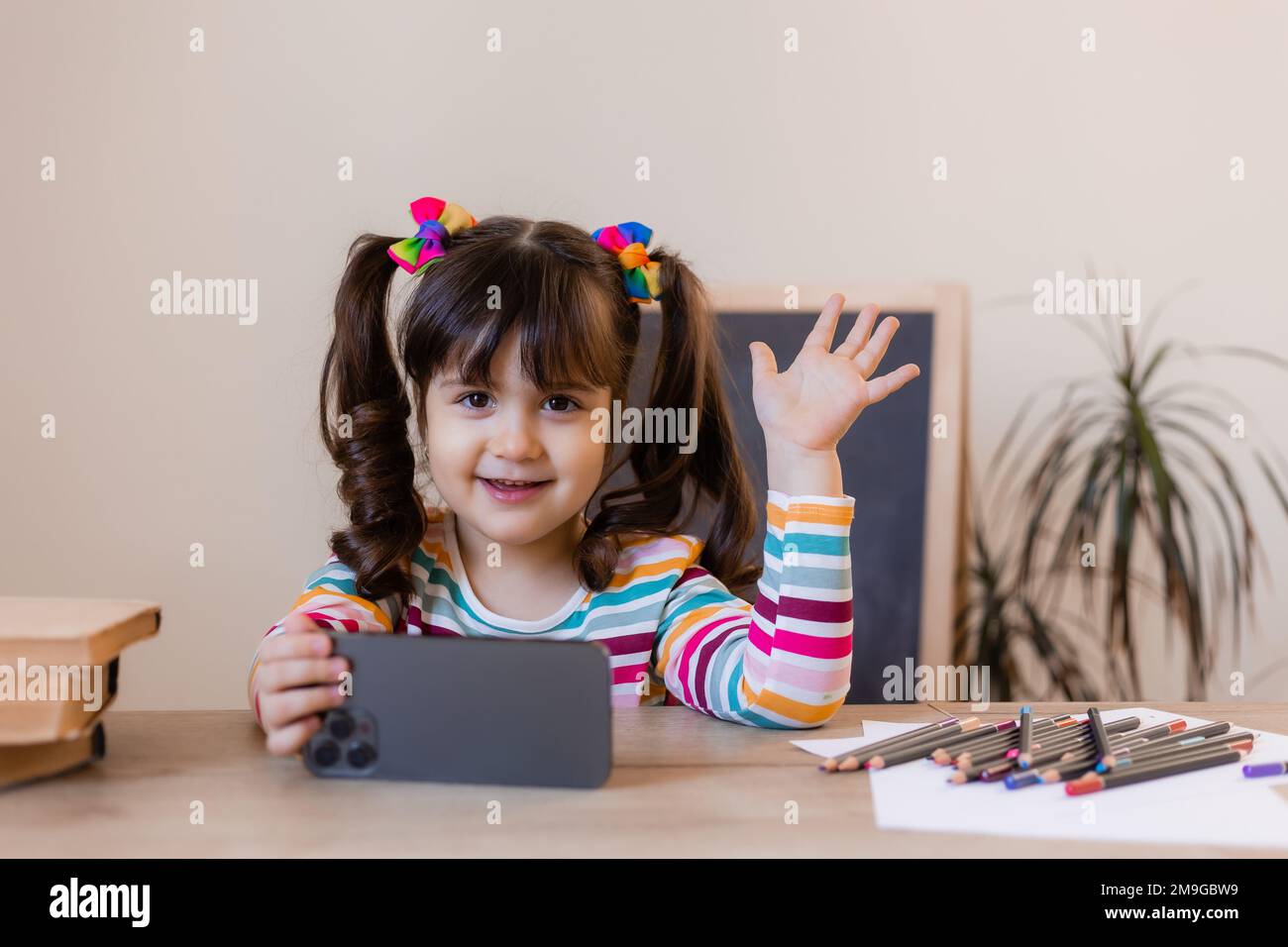 a cute little girl is engaged with a teacher online by phone. Online ...