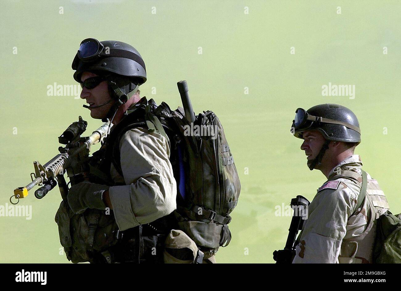 Navy friendly forces members with M-4 Carbine stand on top of a roof for a better view to engage ...