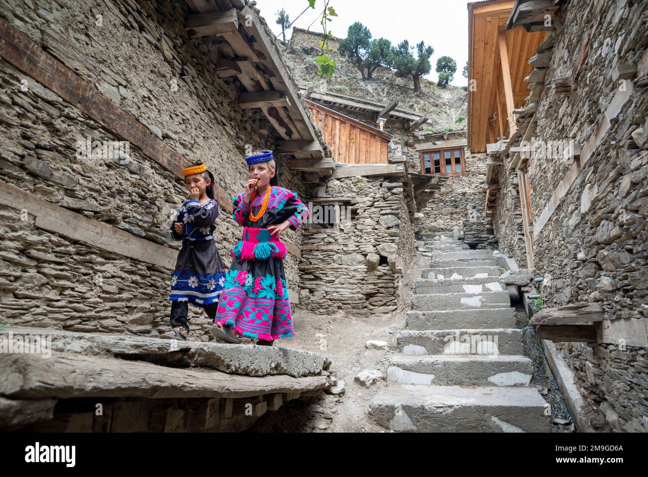 Two young girls wearing traditional attire on the street of a Kalash ...
