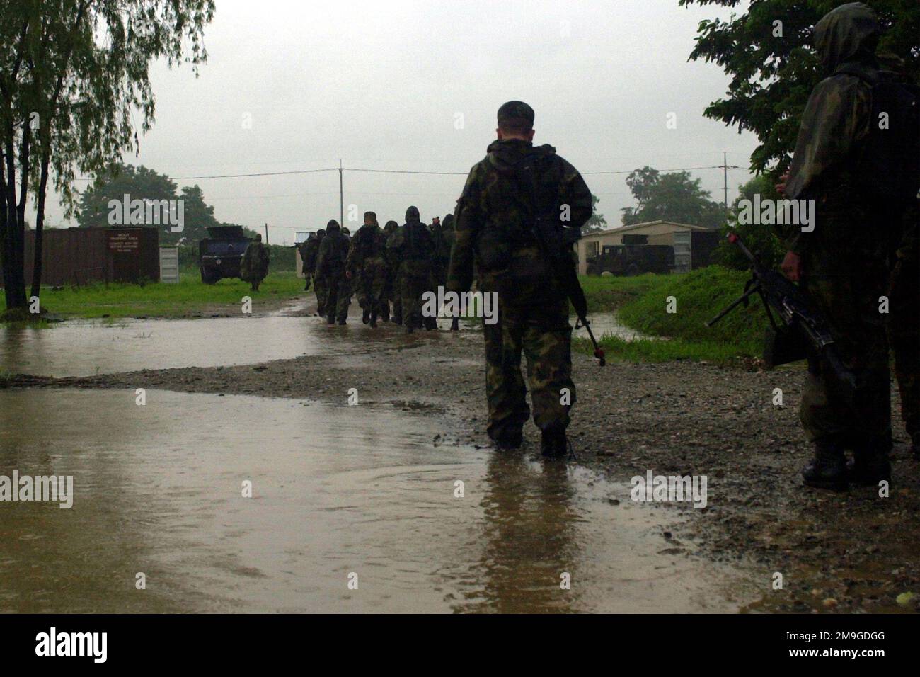 A Security Forces member sloshes through the rain and mud during a ...