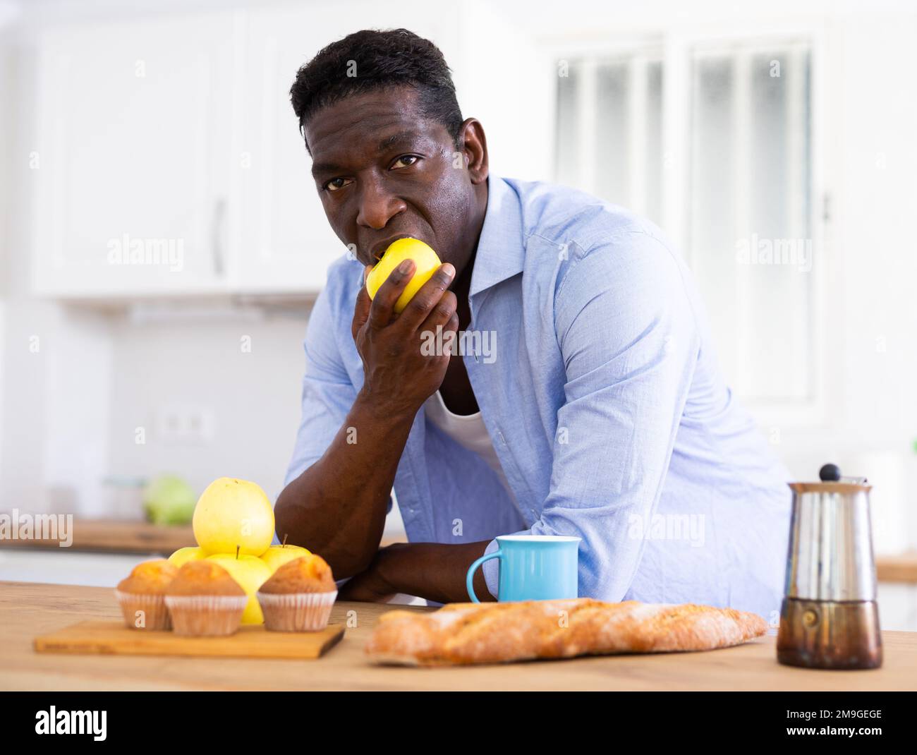 Man eating apple in kitchen at home Stock Photo - Alamy