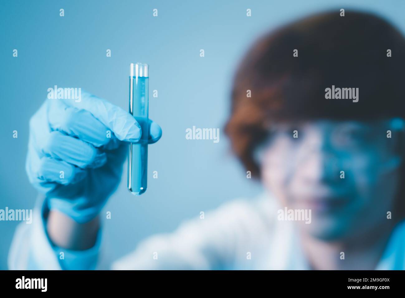 Scientist hand hold test tubes filled with blue sample chemicals in ...