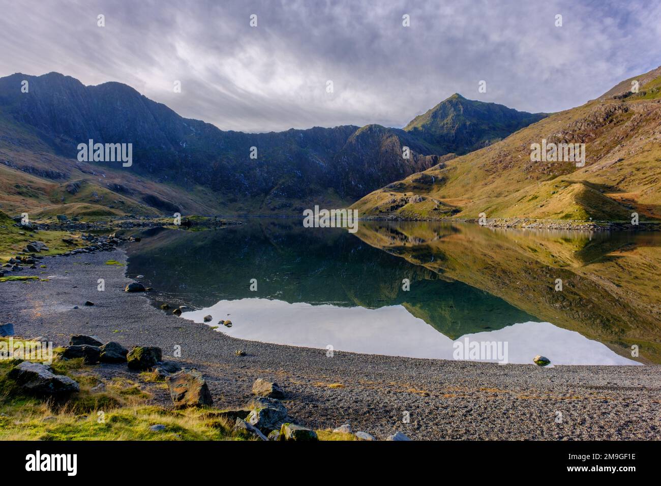 The summit of Snowdon reflected in a lake in Snowdonia National Park ...