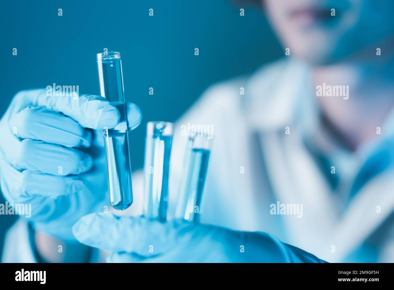 Scientist hand hold test tubes filled with blue sample chemicals in ...