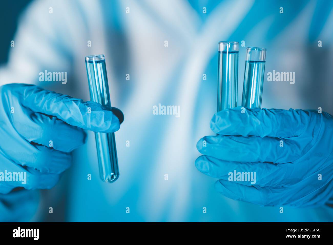 Scientist hand hold test tubes filled with blue sample chemicals in ...