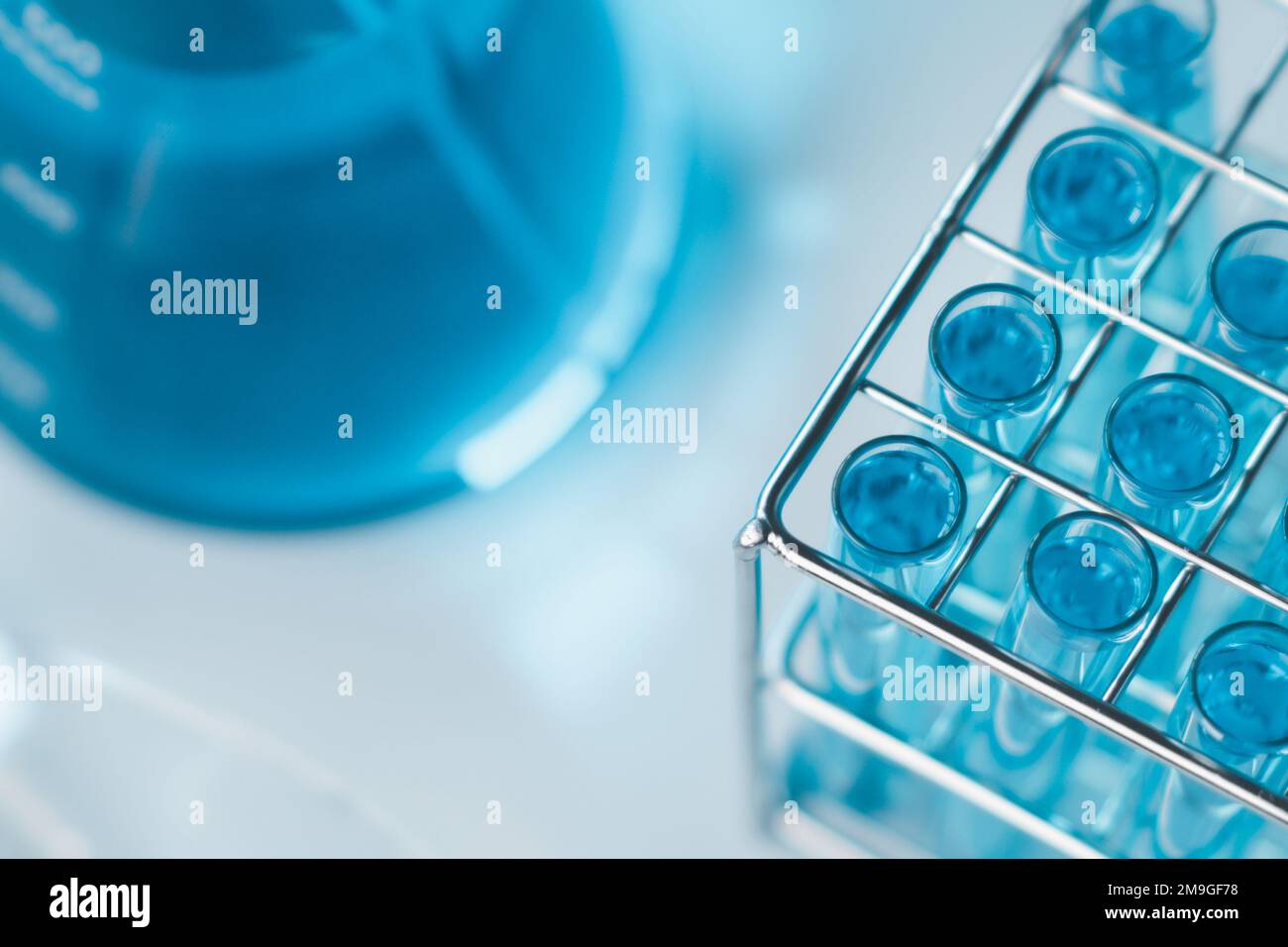 Test tubes and erlenmeyer flask filled with blue sample chemicals in ...