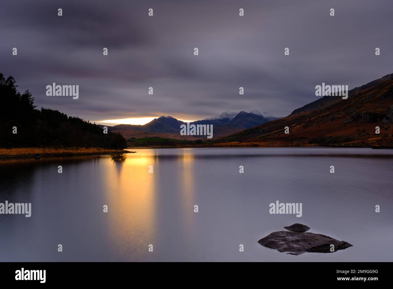 A long exposure image of the Snowdon Horseshoe mountains in a lake in ...