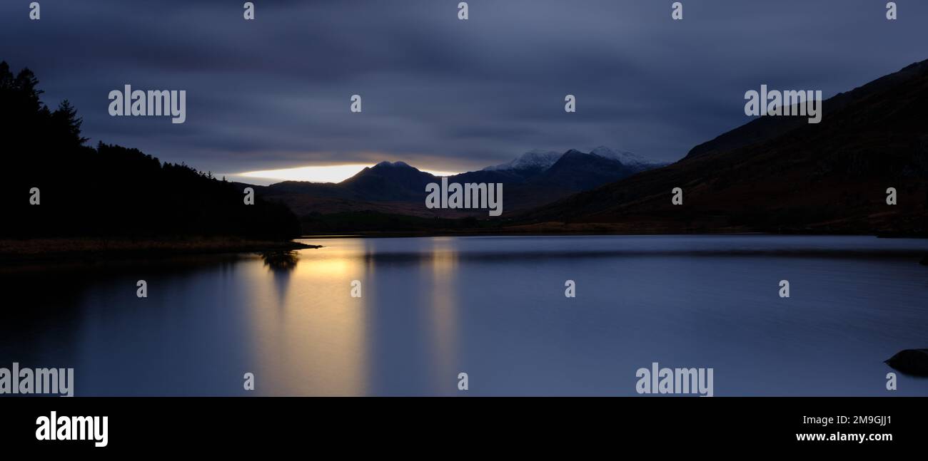 A long exposure image of the Snowdon Horseshoe mountains in a lake in ...