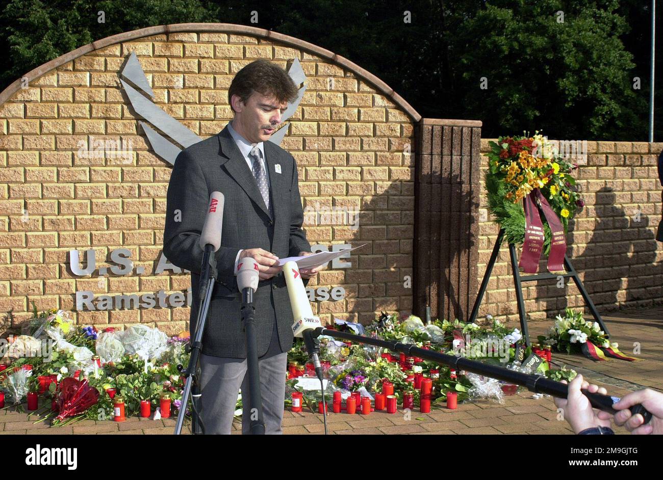 Against a background of wreaths, flowers, and candles at the Ramstein ...