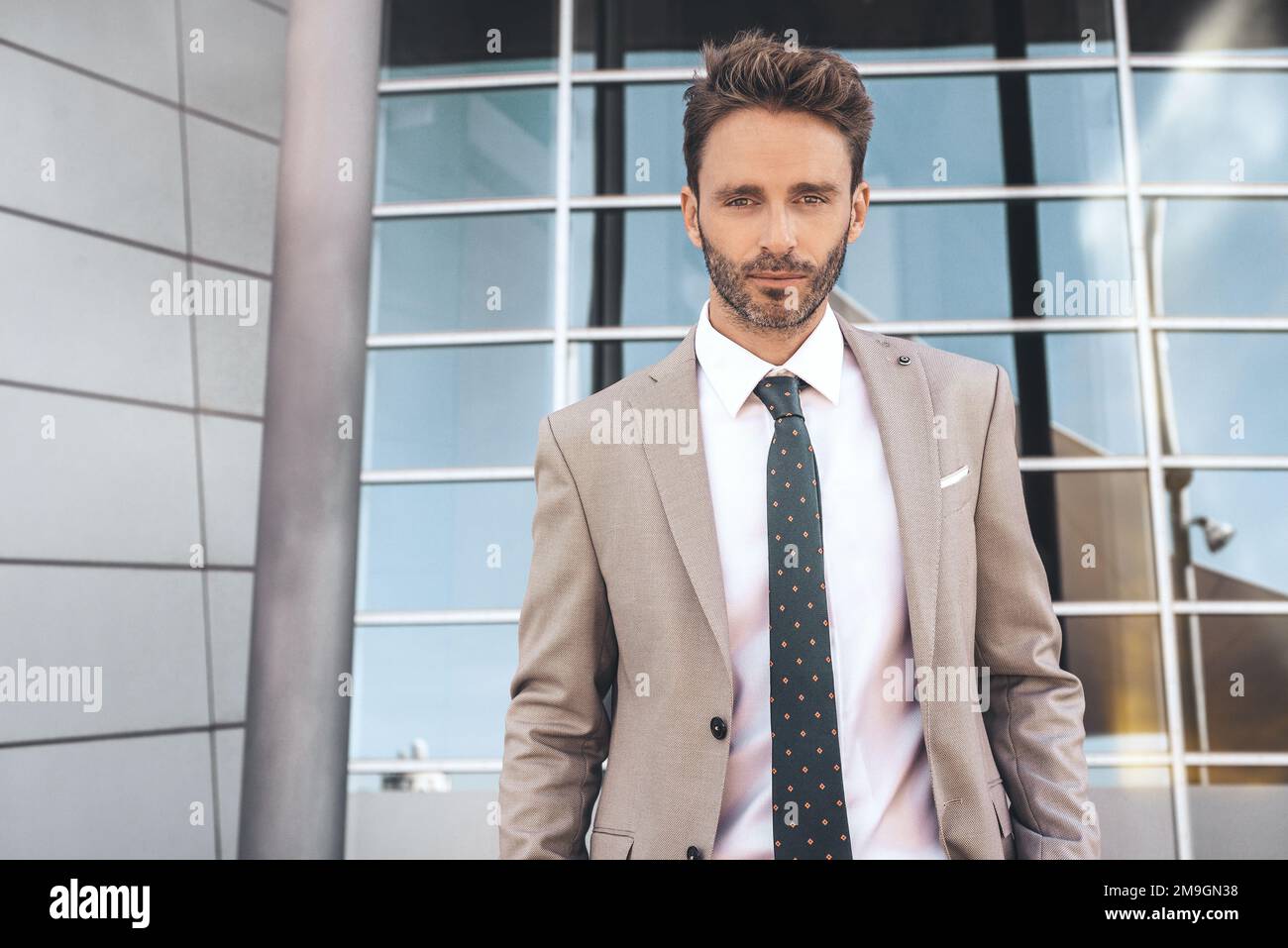 Handsome man model standing by the office building wearing a silver ...