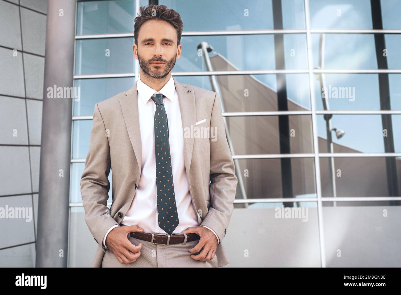 Handsome man model standing by the office building wearing a silver ...