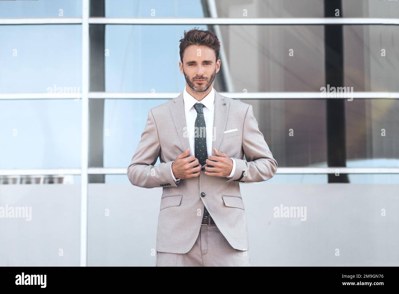 Handsome man model standing by the office building wearing a silver ...