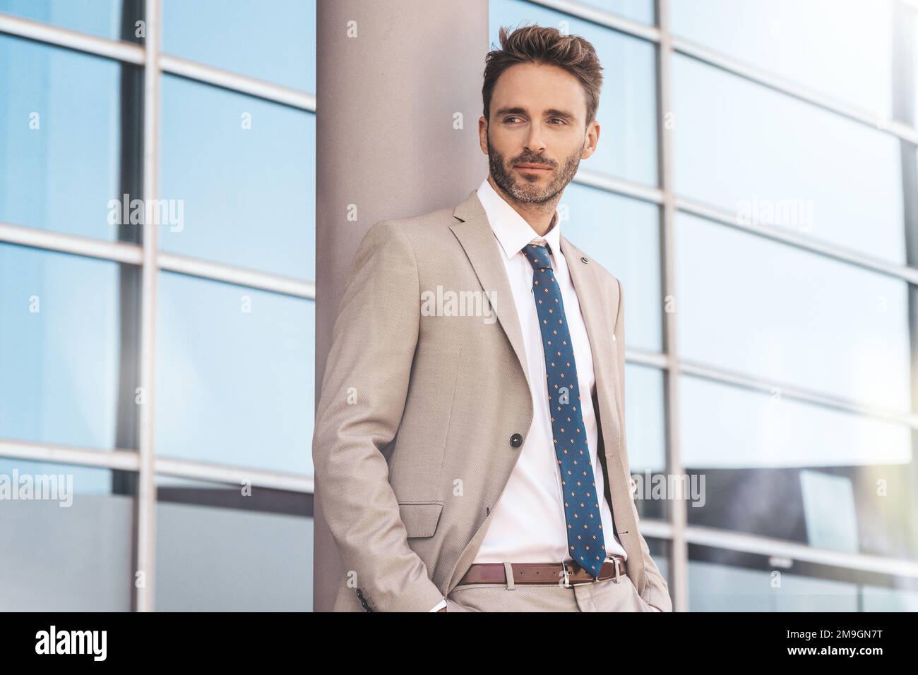 Handsome man model standing by the office building wearing a silver ...