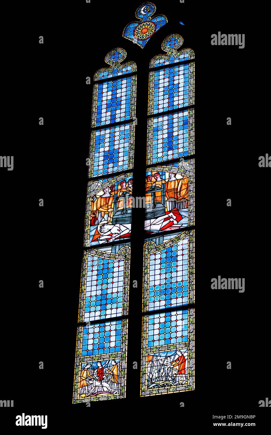 A vertical shot of a long window with stained glass designs in a ...