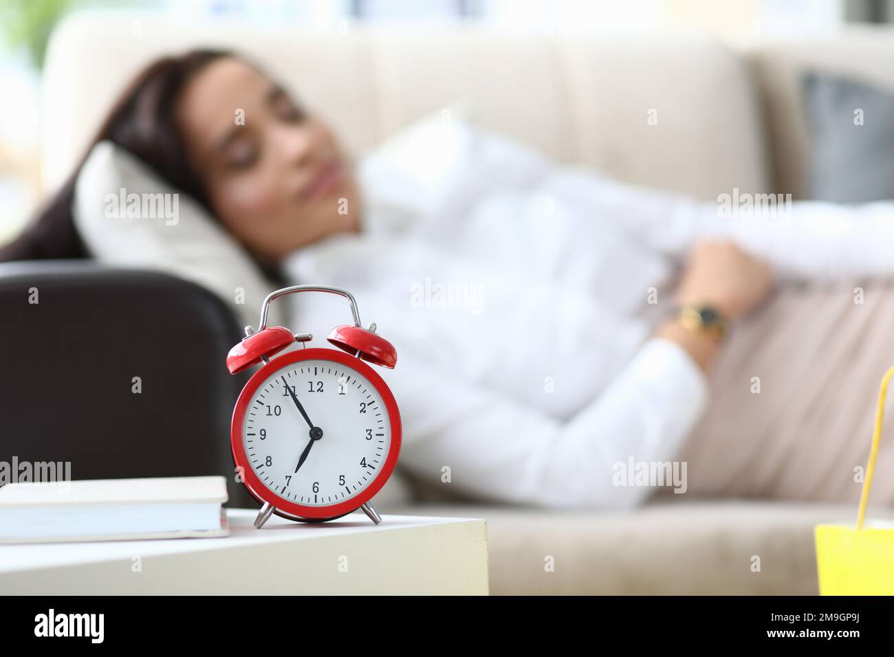 Alarm clock at seven o'clock and woman sleeping on couch Stock Photo ...