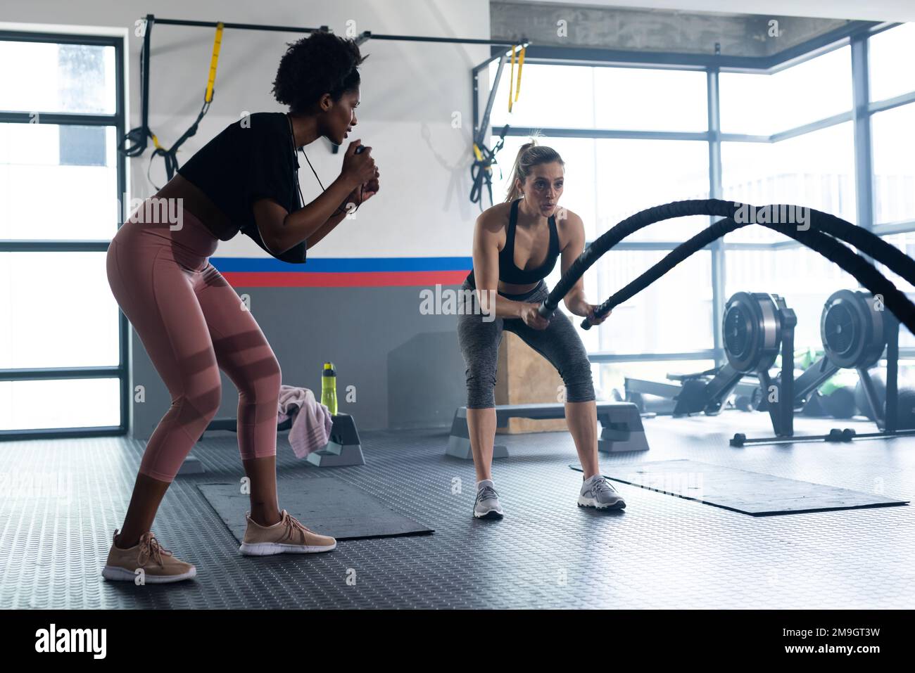 African american female coach with caucasian fit woman exercising with ...