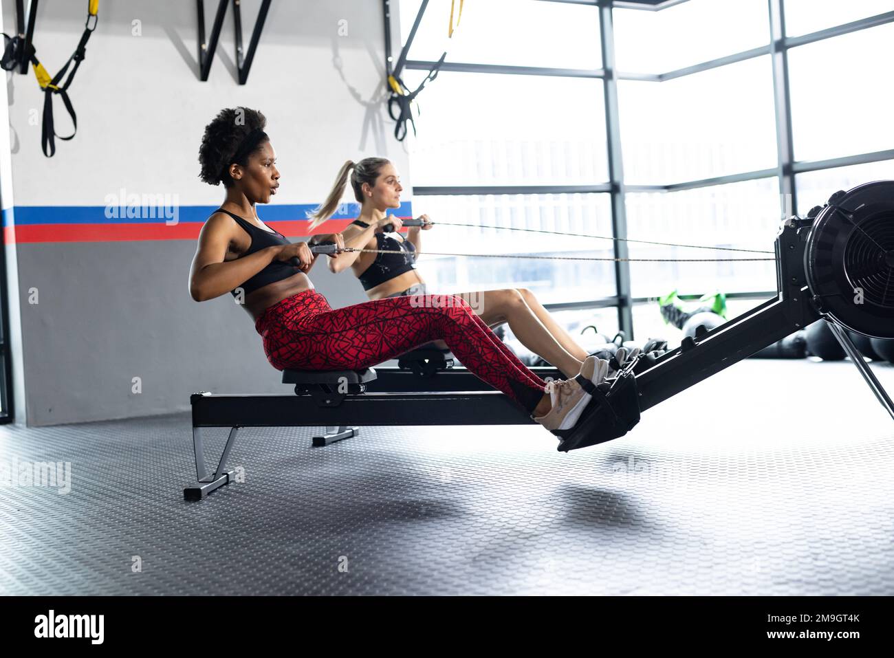 Diverse fit women exercising and using rowing machines at gym Stock ...