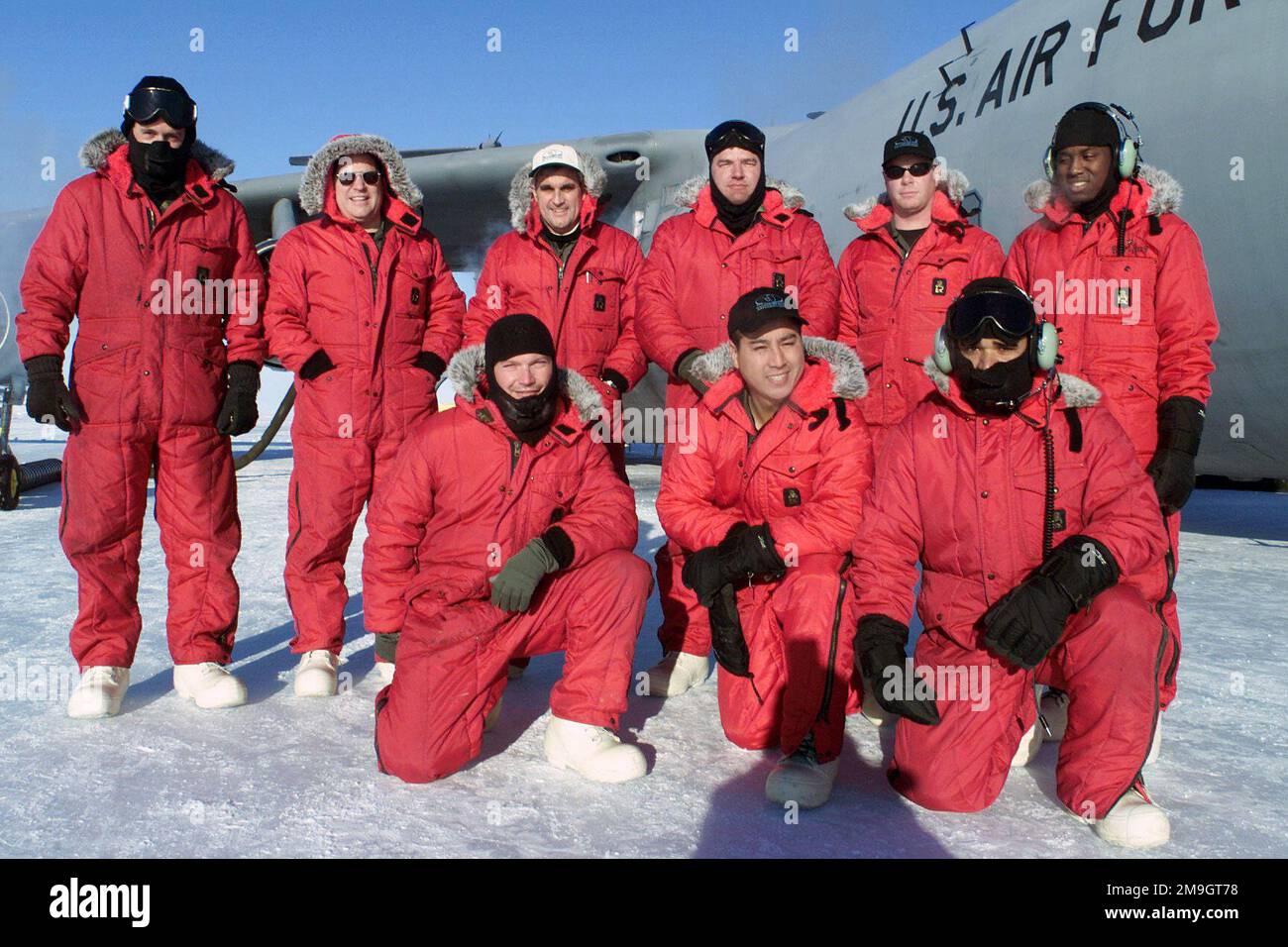Crewmembers pose in their extreme cold weather gear in front of a C ...
