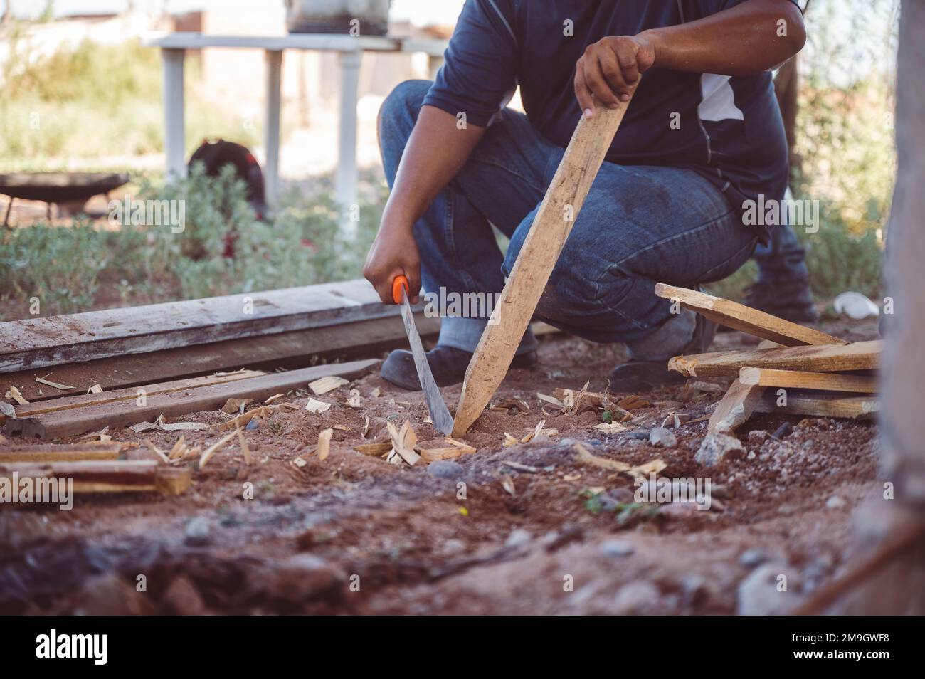 A man, cutting the wooden board with a machete, surrounded by boards ...