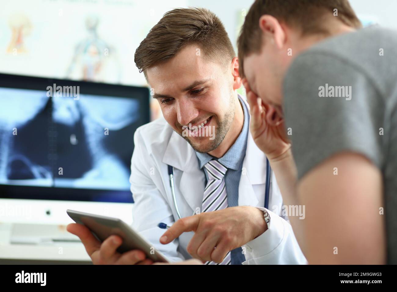 Doctor shows results of medical examination on tablet to sad patient ...