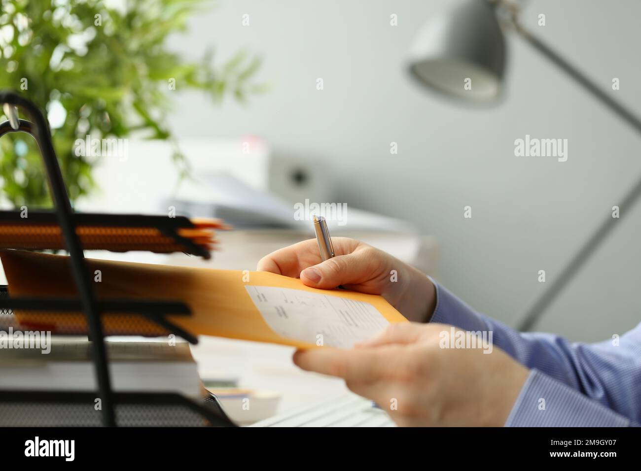 Person picks up yellow envelope with mail at workplace Stock Photo - Alamy