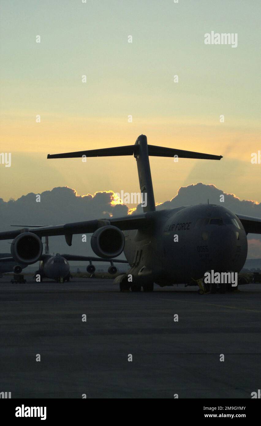 The sun rises over a C-17A Globemaster III and a C-141 Starlifter at ...