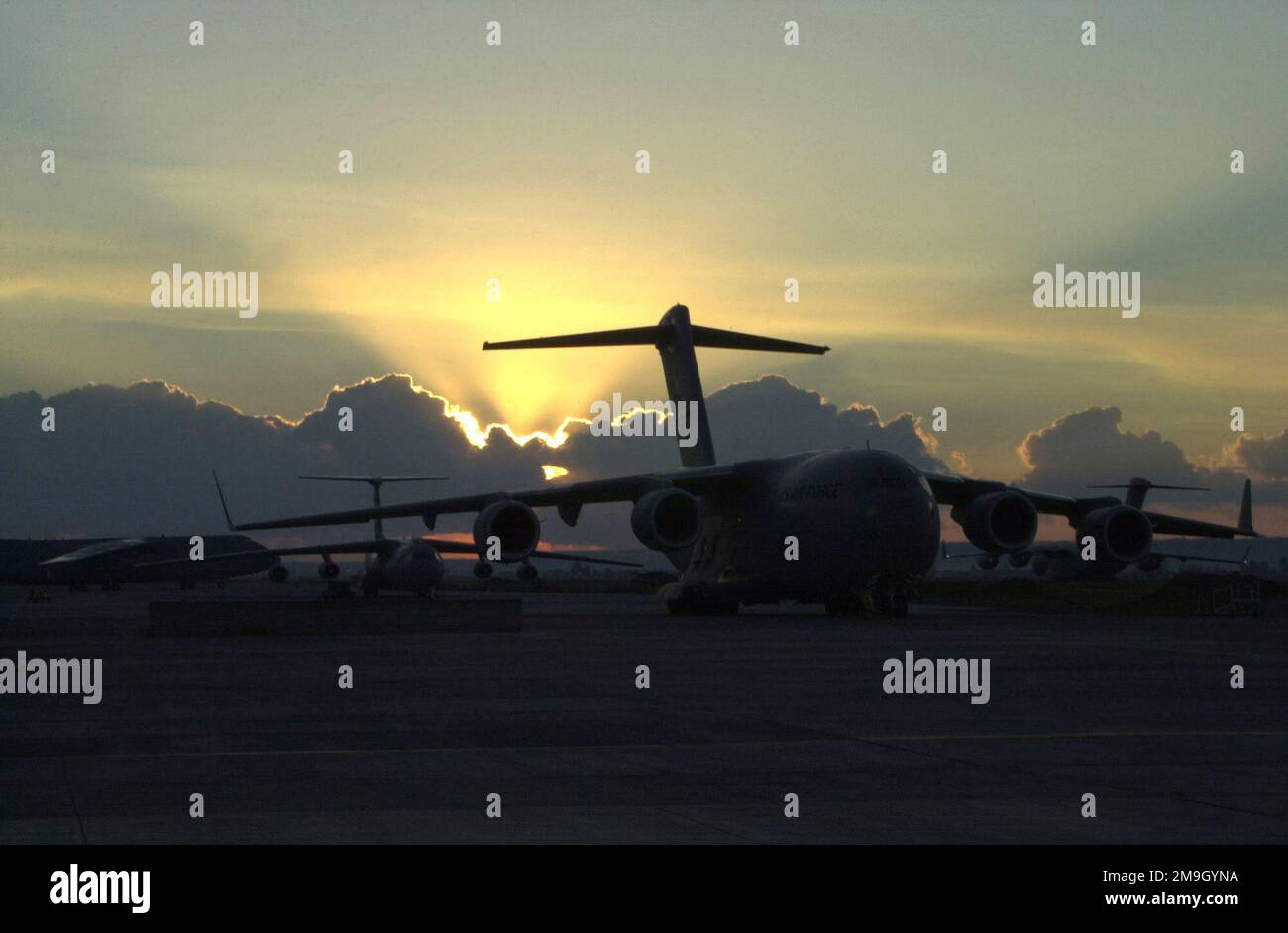 The sun rises over C-17A Globemaster IIIs, a C-141 Starlifter, and C-5 ...