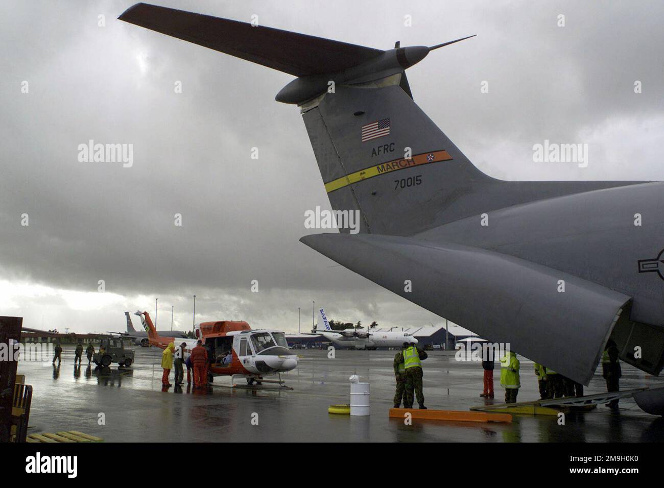 Sitting on the wet ramp without rotor blades, a Bell UH-1N operated by ...