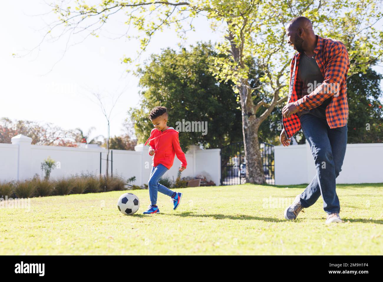 Happy African American Father And Son Playing Football In Their