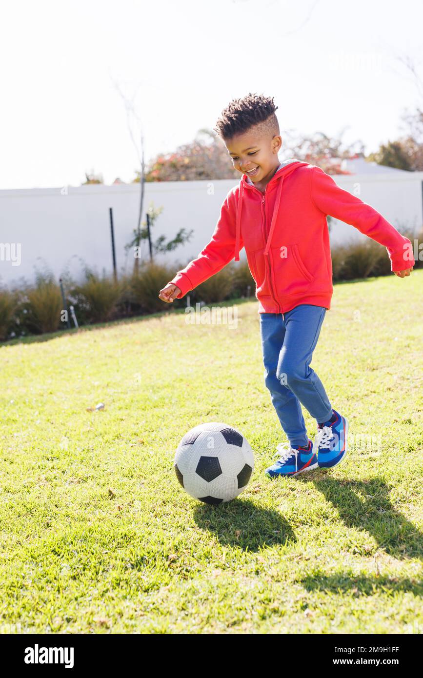 Happy african american boy playing football in backyard Stock Photo - Alamy