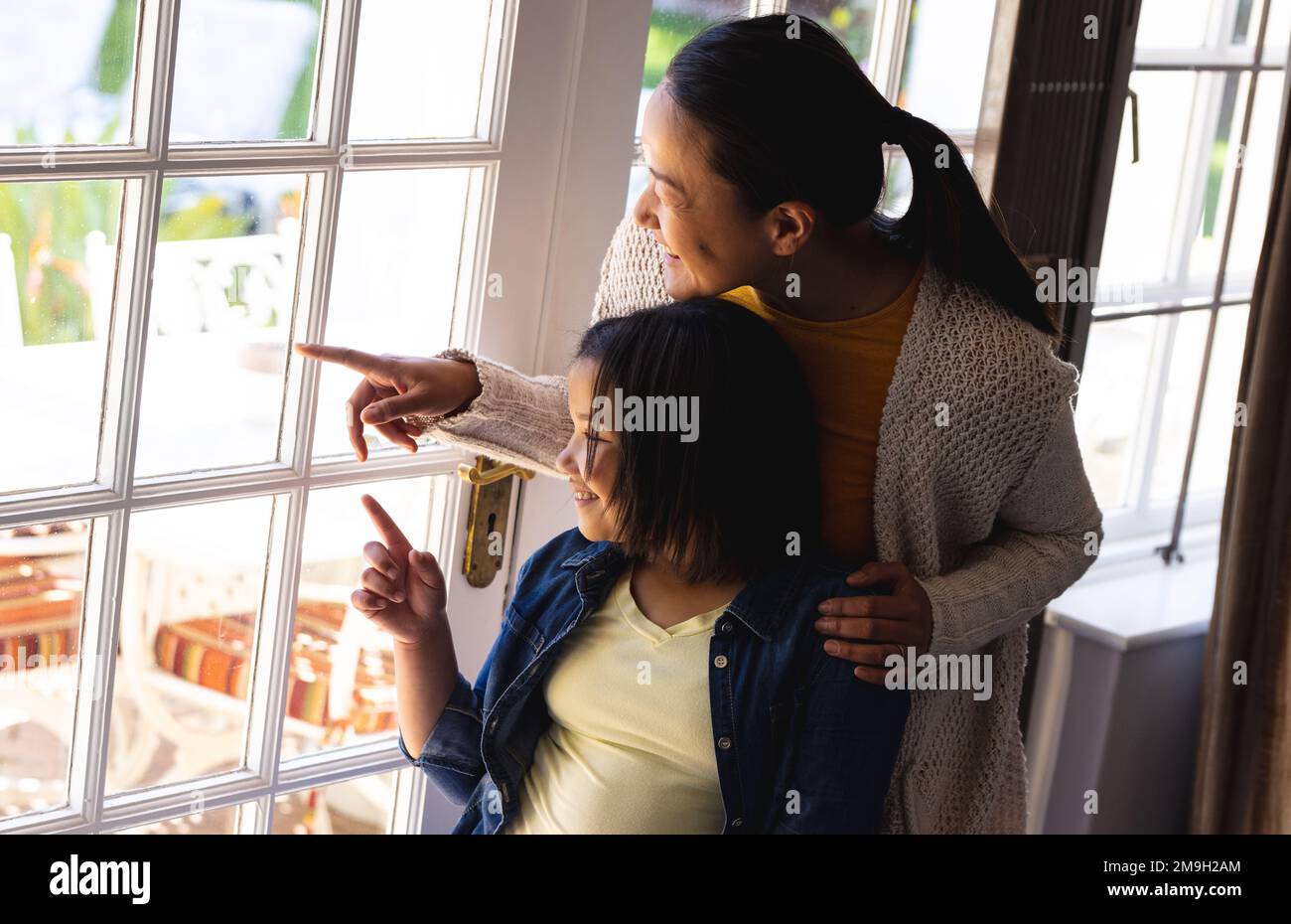 Happy asian mother and daughter looking through window together Stock ...