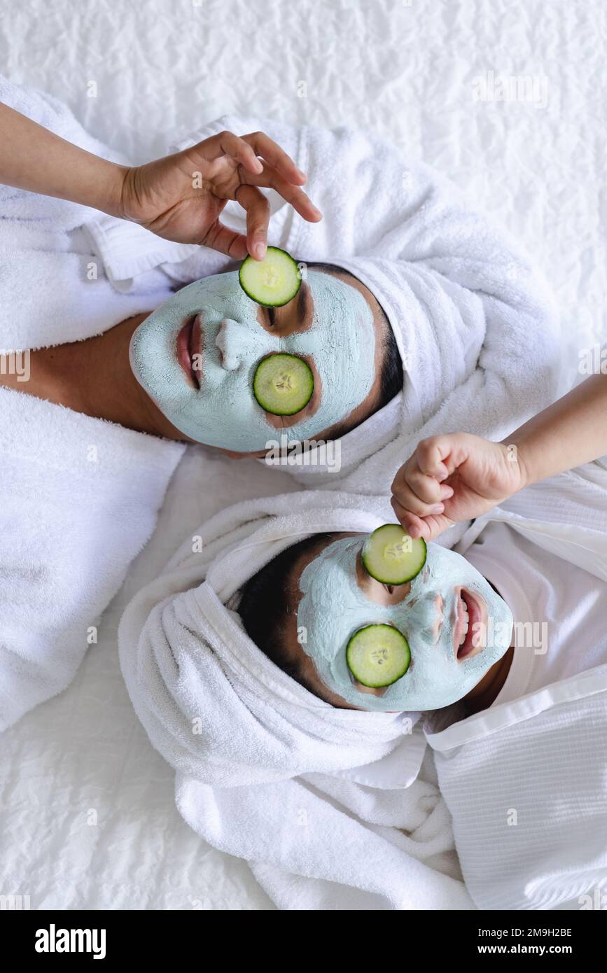 Happy asian mother and daughter laying on bed and wearing beauty face ...