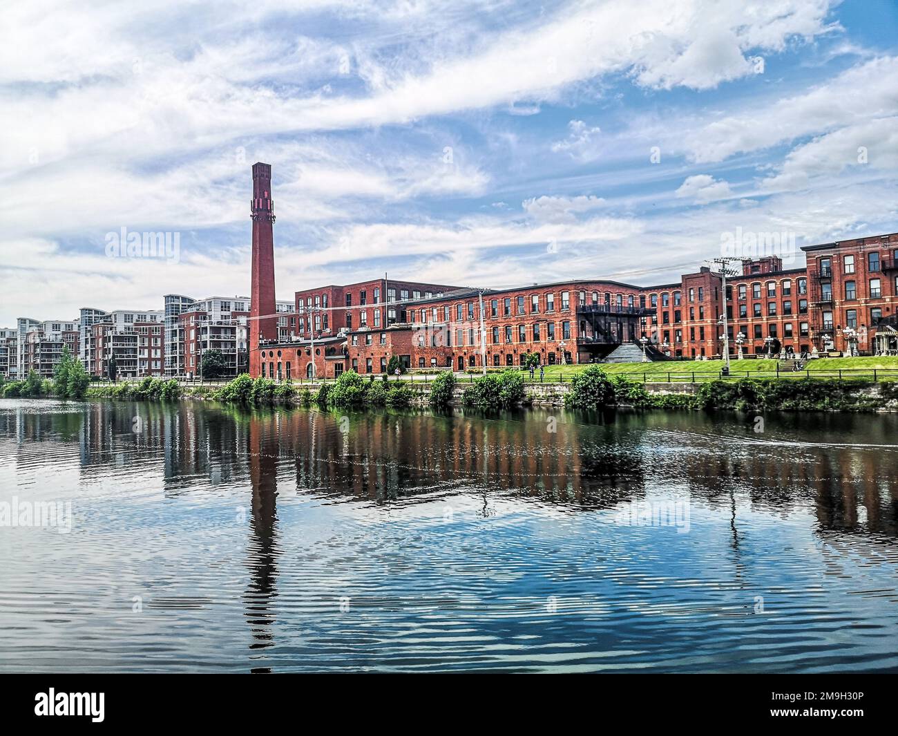 A scenic view of a park with brick buildings surrounding the lake in ...