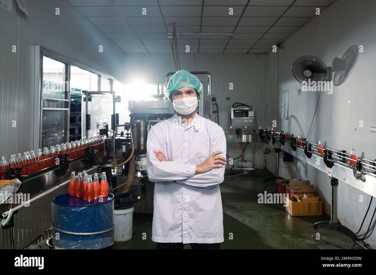 Confident asian supervisor man in sterile suit standing with bottled ...