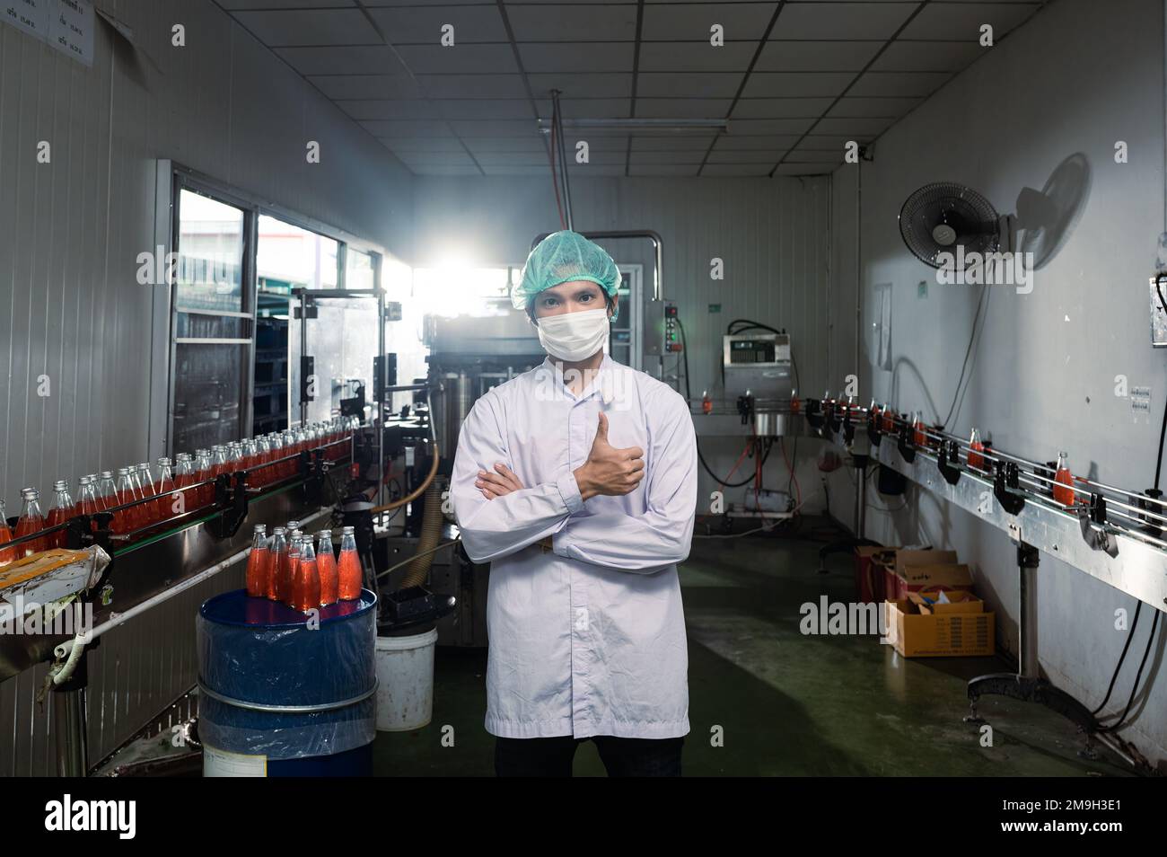 Confident asian supervisor man in sterile suit standing with bottled ...