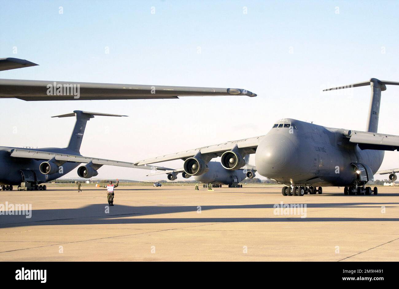 An airman marshals a C-5 Galaxy cargo aircraft through a crowded ...