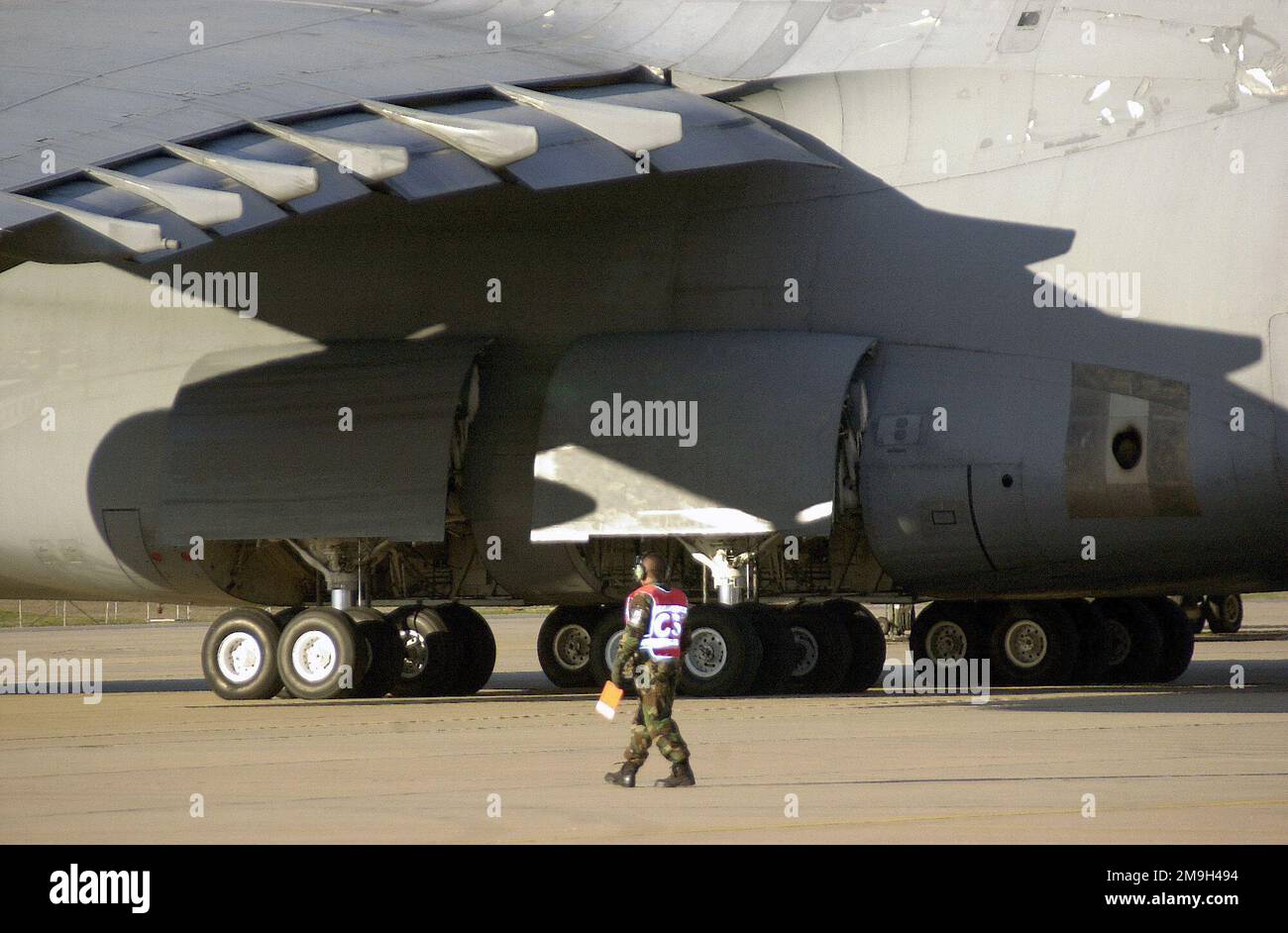 An airman marshals a C-5 Galaxy cargo aircraft through a crowded ...