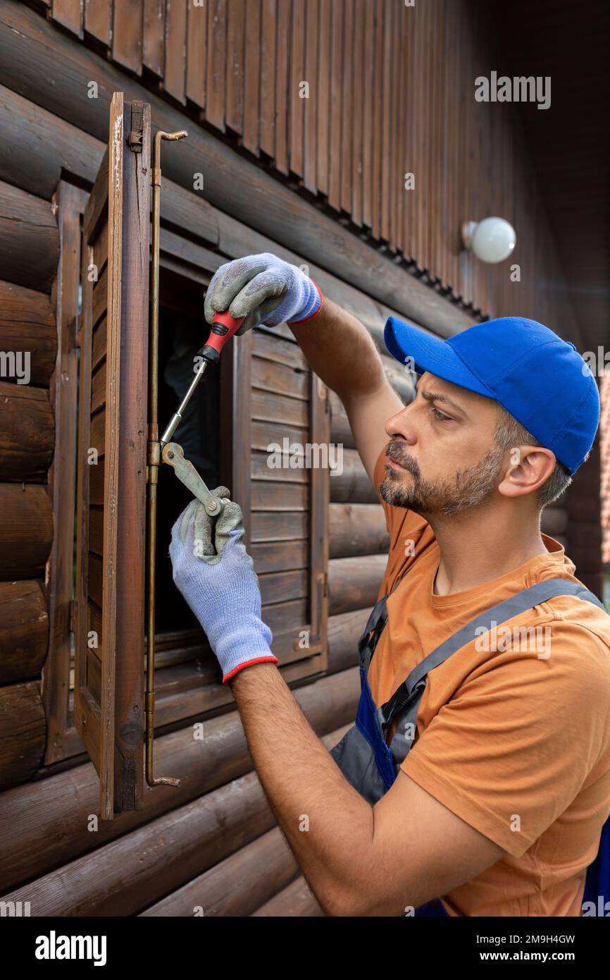 Repairman fixing wooden window shutter by using screwdriver Stock Photo ...