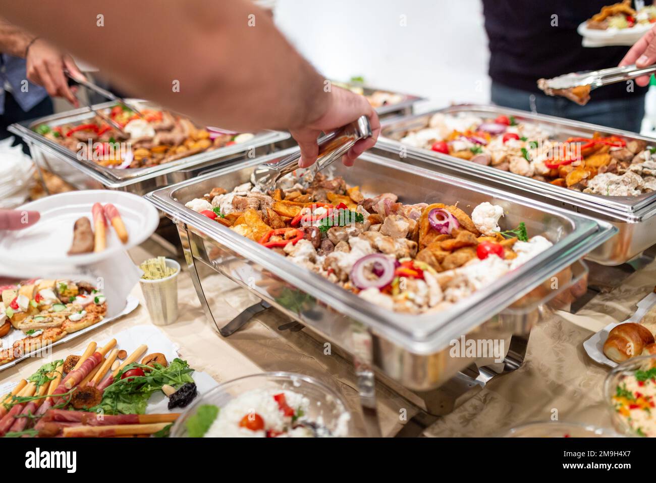 Close up of man hand scooping food with tongs from chafing dish from ...