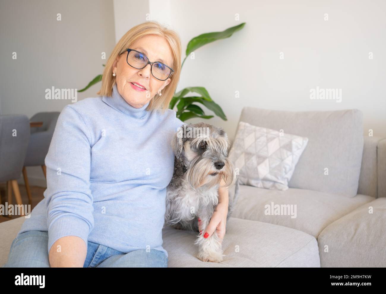 Cheerful senior woman in casual clothing spending time with her dog ...