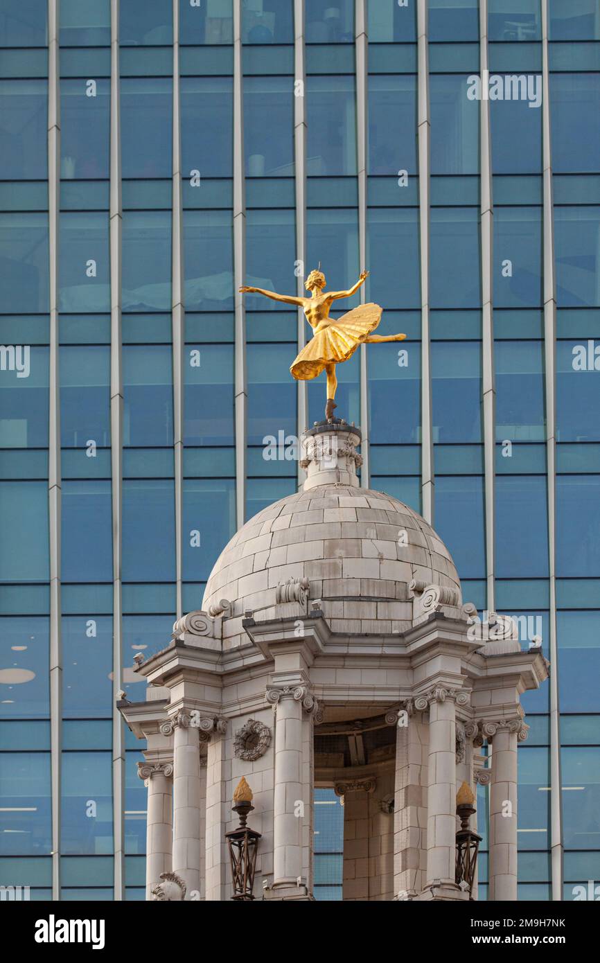 Golden statue of a ballet dancer Pavlova on top of Victoria Palace Theatre in London with modern ...