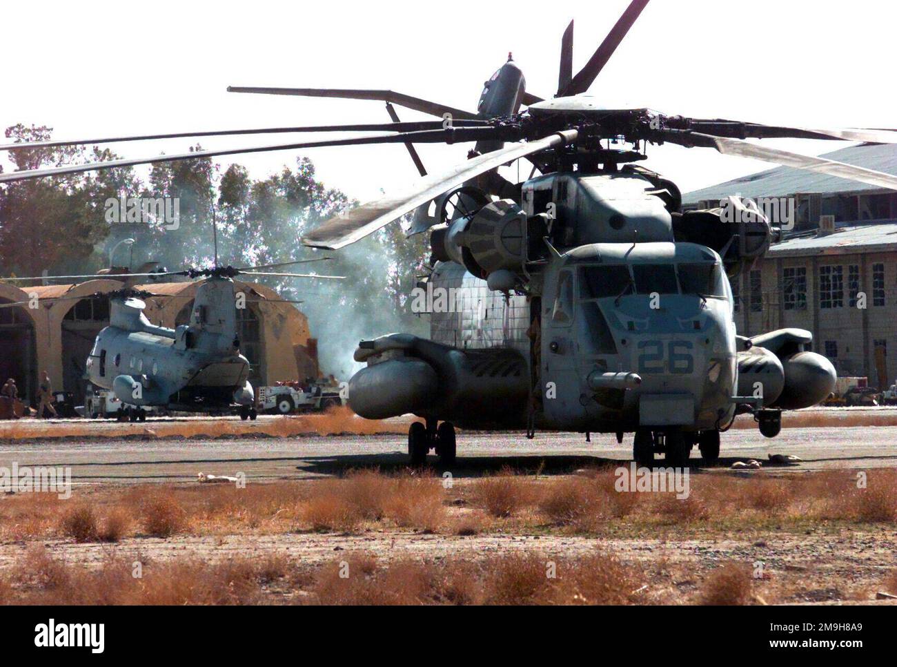 A Marine CH-53 Sea Stallion helicopter sits tail to tail with a Marine ...
