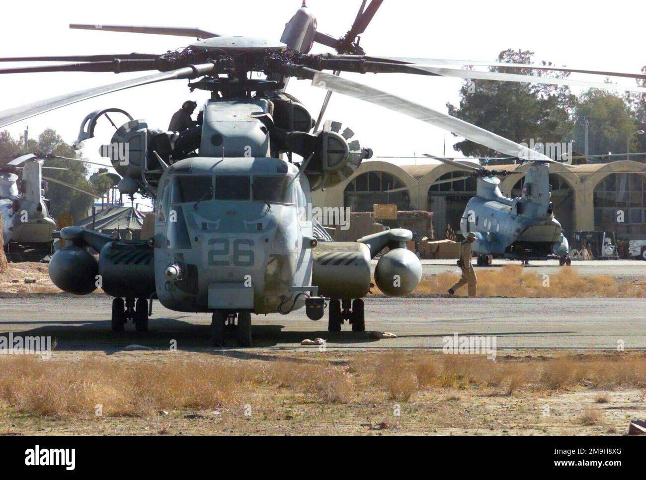 Hidden in the shadow of the helicopter's rotor, a Marine performs ...