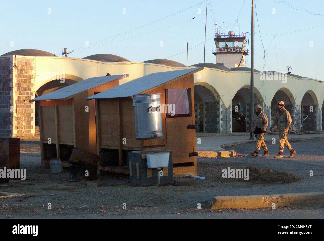 Military personnel walk toward latrines constructed by the US Navy ...