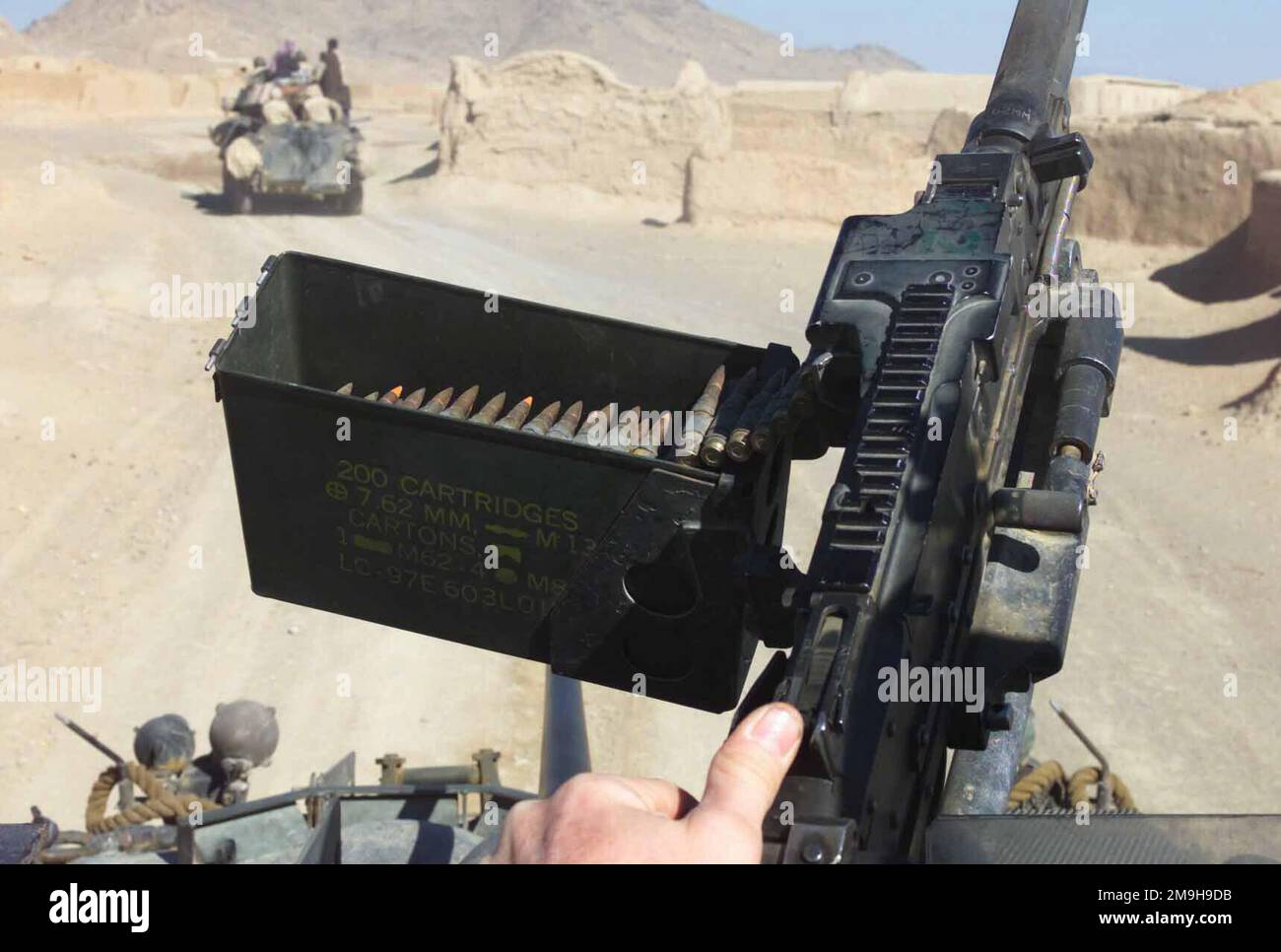 With hands on the M242 25mm chain gun atop the turret of the Light Armored Vehicle-25 (LAV-25) a ...