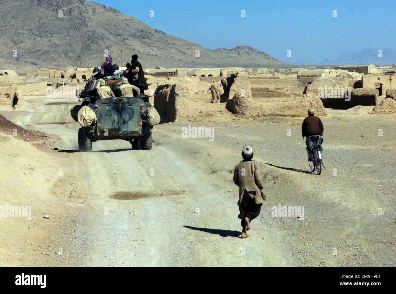 An Afghan boy runs behind a LAV-25 (Light Armored Vehicle) assigned to ...