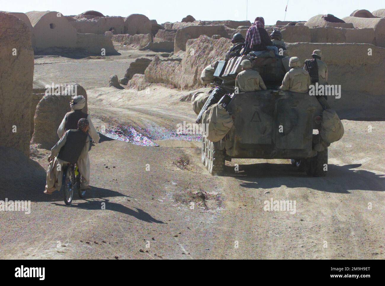 Afghan boys ride a bicycle behind an LAV-25 (Light Armored Vehicle ...
