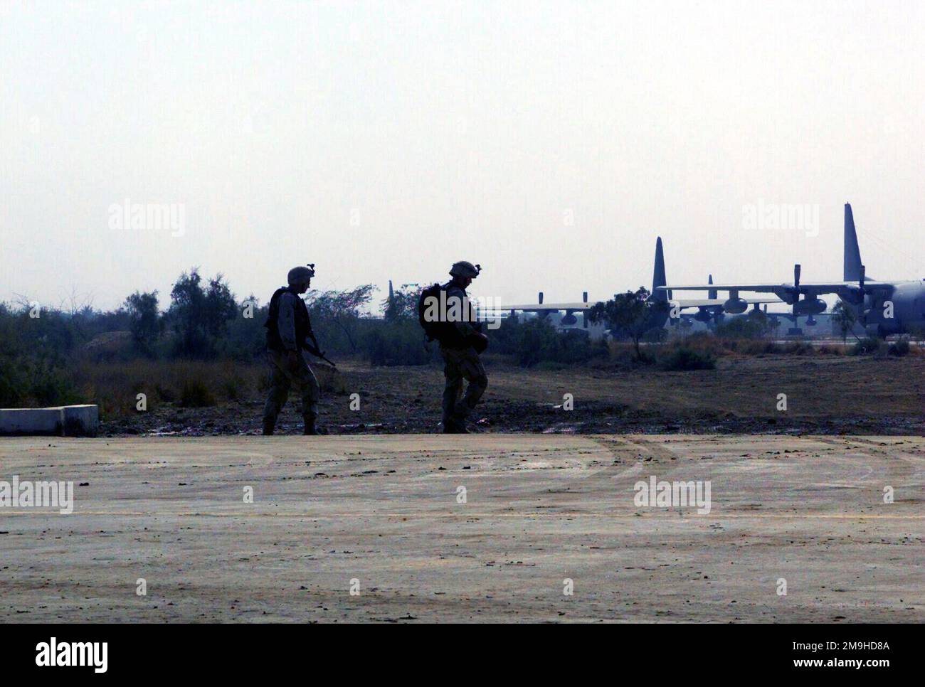 With Marine KC-130/Rs parked on the ramp, two Army Soldiers patrol a ...