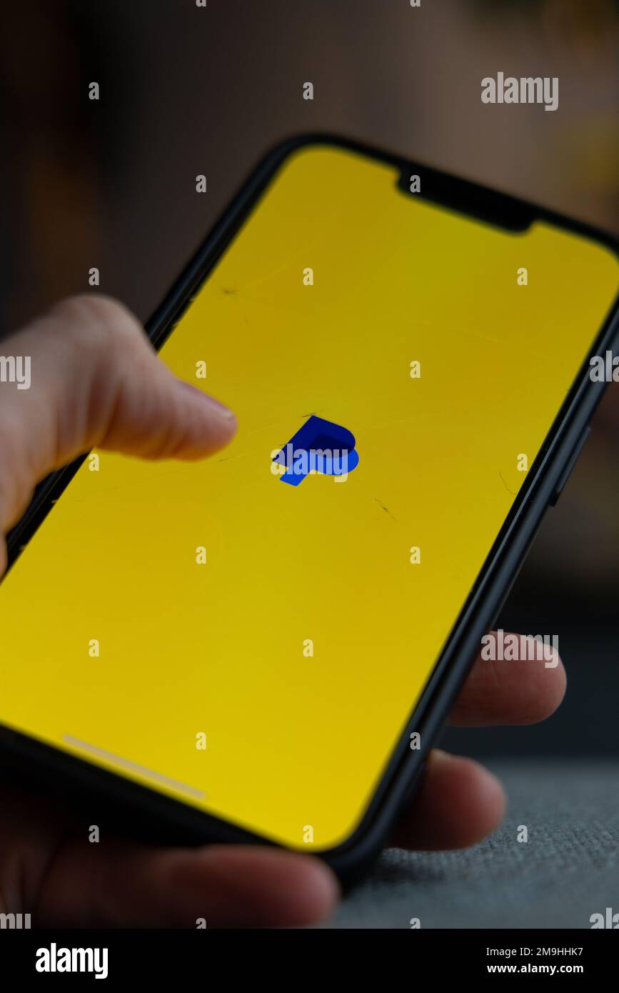 Hand holding a smartphone with PayPal icon on screen. Blue pay pal logo ...