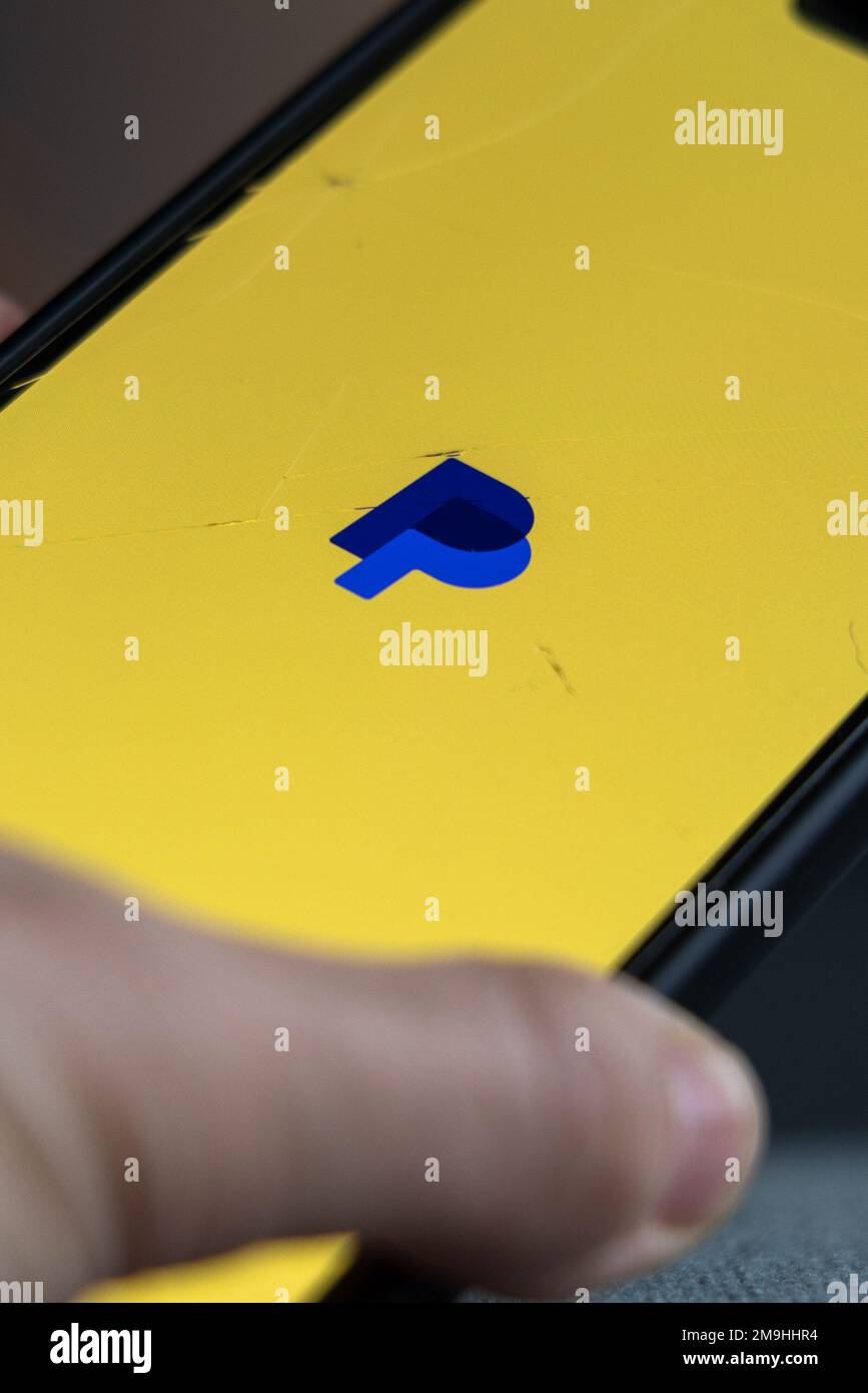 Hand holding a smartphone with PayPal icon on screen. Blue pay pal logo ...